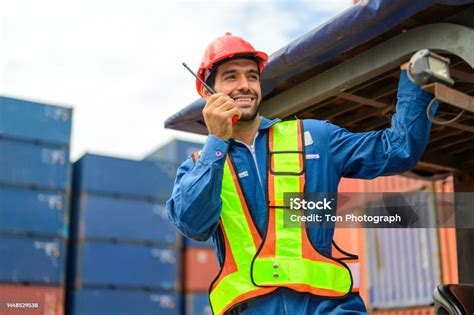 무전기를 사용하여 화물 컨테이너 야적장의 수출입 구역에서 물류 팀과 선적 컨테이너를 통신하고 제어하는 지게차 컨테이너 엔지니어 기술자 건설 기계류에 대한 스톡 사진 및 기타