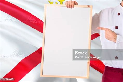 요리사는 저지 국기 배경에 빈 화이트 보드 메뉴를 들고 텍스트에 대 한 균일 한 포인팅 공간을 착용 요리 고급 요리에 대한 스톡 사진 및 기타 이미지 Istock