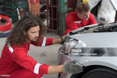 자동차 수리점에서 자동차 부품을 조립하는 남성 자동차 정비사 그룹 차고 작업장에 있는 차의 부속을 일하고 설치하는 기술공의 팀 만들기에 대한 스톡 사진 및 기타 이미지