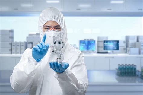 Worker Wears Medical Protective Suit Or Coverall Suit With Small Robot Assistant In Hand Stock