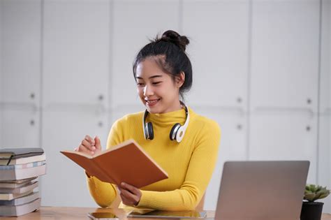 젊은 성인 아시아 학생 여성이 집에서 노트북 컴퓨터를 사용하면서 메모를 하고 있다 온라인 청취 가상 화상 통화를 배우는 아시아 여성 비즈니스와 교육 개념 Brand Name