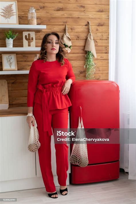 빨간 양복을 입은 아름다운 여성이 빨간 냉장고 근처 부엌에 서 있다 20 29세에 대한 스톡 사진 및 기타 이미지 20 29