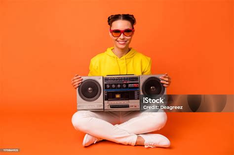 주황색 배경 위에 고립 된 안경 안경 노란색 스웨터를 입고 웃는 붐 박스를 들고있는 매력적인 여성의 초상화 갈색 머리에 대한 스톡 사진 및 기타 이미지 Istock