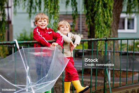 비오는 날에 야외에서 큰 우산을 들고 걷는 두 명의 어린 소년 가장 친한 친구 및 형제 자매 유치원 아이들이 재미있습니다 고무 부츠와 사랑스러운 아이 악천후 당일 가족 야외