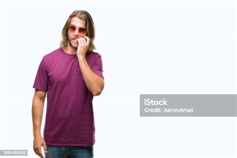 격리 된 배경 찾고 스트레스와 긴장에 선글라스를 쓰고 긴 머리를 가진 젊은 잘생긴 남자는 손톱을 물어 뜯고 입에 손 불안 문제입니다 감정에 대한 스톡 사진 및 기타 이미지