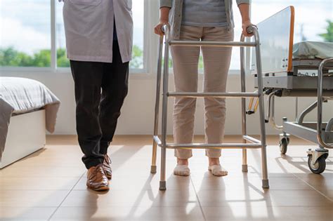 의사는 보행기를 사용하여 노인 환자 여성을 지원하고 병원의 방에서 걷기를 시도합니다 사고 후 물리 치료 걷는 동안 통증을 느낍니다 의료 보험 및 의료 의료 개념 3 명에