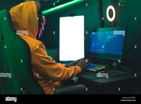 Hacker In An Orange Hood And With A Mask Hacking Databases Medium Shot