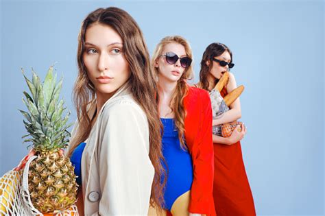 빨강과 파란색 수영복과 벌거 벗은 몸에 트렌치 코트를 입은 세 명의 젊은 유행 여성 주부 손에 음식이 있는 쇼핑객 스트립 백 쇼핑 구매 및 소비주의 아름다운 긴 다리 20