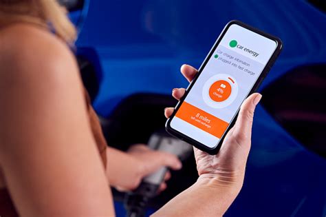 배터리 잔량을 모니터링하기 위해 휴대 전화에서 앱을 사용하여 케이블로 전기 자동차를 충전하는 여성 깨끗한에 대한 스톡 사진 및 기타 이미지 Istock