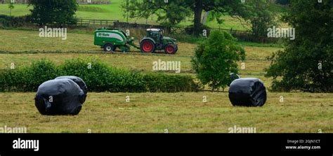 Hay And Silage Making Farmer In Farm Tractor At Work In Rural Field