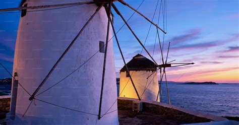 유명한 미코노스 코라 마을 풍차의 경치 그리스 키클라데스 제도의 저녁에 조명이 켜진 미코노스 섬의 전통 그리스 풍차 스테디캠과 함께 걷기 사진 Unsplash의