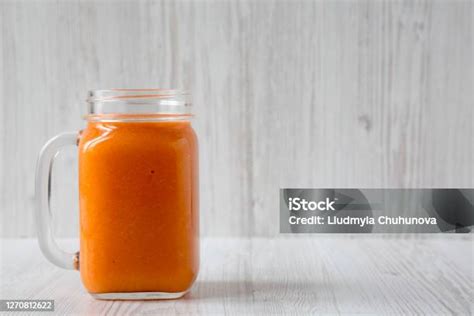 흰색 나무 표면 측면 보기 위에 유리 항아리 머그잔에 집에서 만든 망고 당근 스무디 공간을 복사합니다 0명에 대한 스톡 사진 및