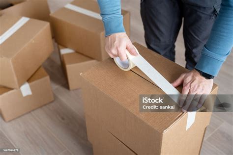한 남자가 접착 테이프를 사용하여 골판지 상자를 포장합니다 이사 개념 이주 개념에 대한 스톡 사진 및 기타 이미지 이주 개념