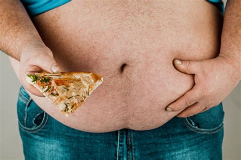 회색 배경에 피자 조각을 가진 뚱뚱한 남자 건강에 해로운 음식의 개념 건강관리와 의술에 대한 스톡 사진 및 기타 이미지 건강