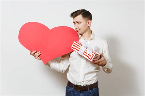 불만족된 남자 셔츠 큰 빨간 마음을 잡고 흰색 배경에 고립 된 선물 상자를 제시 광고에 대 한 공간을 복사 합니다 세인트 발렌타인 날 국제 여성의 날 생일 휴가 개념 14에