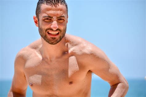 Premium Photo Portrait Of Smiling Shirtless Man At Beach Against Clear Sky
