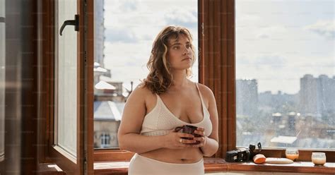 열린 창문에 서서 집에서 술을 마시는 특대 여성 신체 양성 페미니즘의 아이디어 국내 생활 방식 문신을 한 젊은 사려 깊은