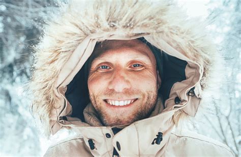 따뜻한 후드 캐주얼 파카 재킷 아우터웨어를 입고 눈 덮인 숲에서 걷는 남자 쾌활한 웃는 얼굴 초상화 아웃 도어 타임 및 겨울 의상 컨셉 이미지입니다 가족에 대한 스톡 사진