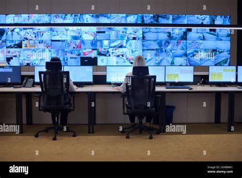 Group Of Security Data Center Operators Working In A Cctv Monitoring Room Looking On Multiple