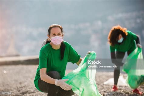 여성 자원봉사자들은 쓰레기 플라스틱으로 해변을 청소하고 녹색 쓰레기 봉투를 들고 환경 관리를 합니다 25 29세에 대한 스톡