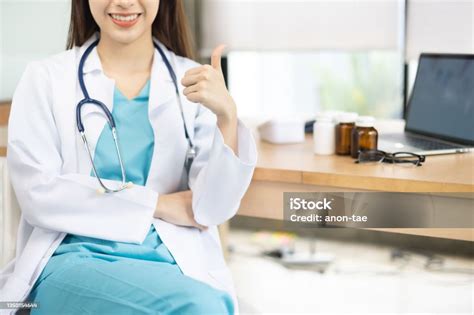 청진기를 가진 백인 의료복을 입은 자신감 있는 젊은 아시아 여성 의사가 카메라를 바라보고 웃는 건강 병원을 바라보고 있습니다 사무실에서 웃는 의사의 초상화 20 24세에