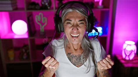 Cheerful Middle Age Grey Haired Woman Streamer Confidently Playing A