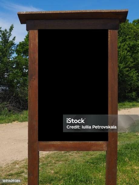 텅 빈 검은색 수직 직사각형 철탑이 숲 비포장 도로 모형에 서 있습니다 광고 판촉 모형을 위한 빈 패널 회사 광고 템플릿에 대한 캔버스 프레임 배너를 지웁니다 프루스카 고라