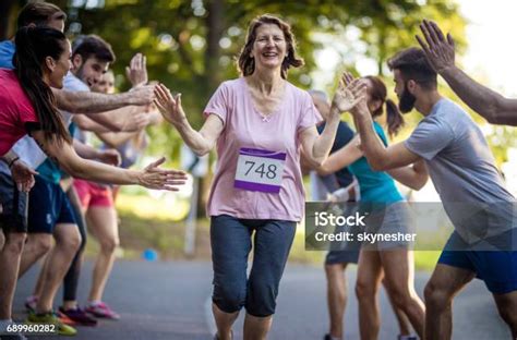 성숙한 여자 마라톤 레이스를 마무리 하 고 지지자 그룹 인사 마라톤에 대한 스톡 사진 및 기타 이미지 마라톤 결승선 오프 트랙 러닝 Istock
