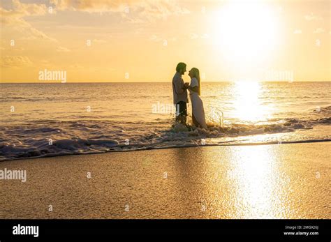 Young Well Dressed Couple Holding Hands As Ocean Waves Crash Into Them