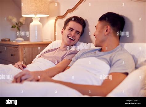 Loving Same Sex Male Couple Lying In Bed At Home Holding Hands Together
