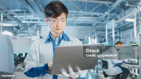 하이테크 공장에서 아시아 엔지니어는 설치를 위한 노트북 컴퓨터를 사용 하 여 인쇄 회로 기판 표면 실장 조립 라인에 대 한 전자