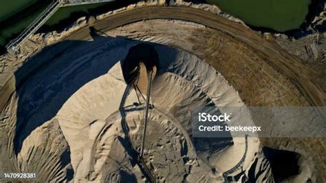 노천 모래 광산의 아리알 전망 프론트 로더는 더미에서 모래를 적재합니다 채석장에서 일하는 무거운 광산 기계 많은 바퀴 트랙과 사막 모래 언덕이나 가슴과 같은 모래 더미 건조