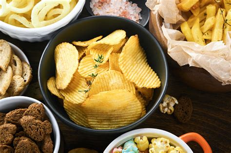 건강에 해로운 음식이나 간식 땅콩 팝콘 양파 반지와 소금에 절인 프레첼을 오래된 나무 배경의 그릇 접시에 담은 모든 고전적인 감자 스낵 인물 심장 피부 치아에 대한 건강에