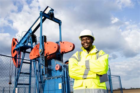 보호 장비를 착용하고 안전모를 쓴 유전 엔지니어가 펌프 잭 앞에 서 있다 가솔린에 대한 스톡 사진 및 기타 이미지 가솔린 굴착 장치 기체 물리 구조 Istock
