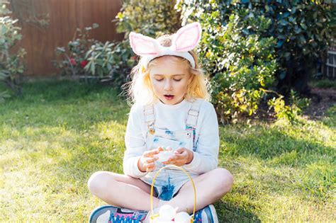 부활절 초콜릿 달걀 과자 정원에서 달걀 사냥 후 사탕이 담긴 열린 용기를 들고 토끼 귀를 입은 어린 소녀 부활절 휴일에 즐거운 시간을 보내는 아이 과자를 먹는 아이들 선택적