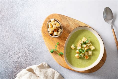 녹색 야채 브로콜리 녹색 완두콩 시금치의 디톡스 크림 수프는 회색 콘크리트 배경에 Crutons와 마이크로 그린과 함께 제공됩니다 봄 디톡스 레시피 건강 식품 개념 평면도