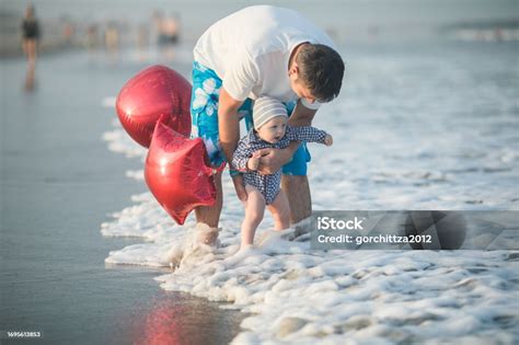 갓난아기 아들과 함께 해변에서 즐거운 시간을 보내는 쾌활한 젊은 아버지 공중에 아이를 던지는 아빠 2명에 대한 스톡 사진 및