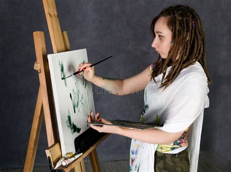 El Artista De Sexo Femenino De La Pintura Que Presenta Al Lado De Un Caballete Y De Las Pinturas