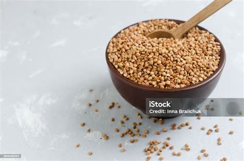 회색 배경에 나무 숟가락이 있는 갈색 그릇에 유기농 건조 메밀 가루 채식주의자 및 비건 음식 건강한 식생활의 개념 수평 방향 공간을 복사합니다 0명에 대한 스톡 사진 및