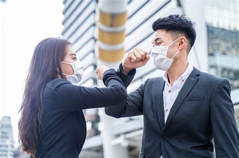 아시아 기업인들은 공방19 전염병 위기로 인해 도시 밖에서 보호얼굴 마스크를 착용하고 있습니다 코로나바이러스 감염을 피하기 위해 악수 대신 팔꿈치 범프를 만드는 남성과 여성