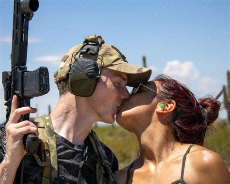 Couple Holding Assault Weapons And Guns Kissing Close Up While Wearing Tactical Gear Stock Photo
