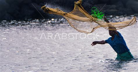 صياد عربي خليجي سعودي يقوم برمي شبكة الصيد في شاطئ جازان، الشواطئ