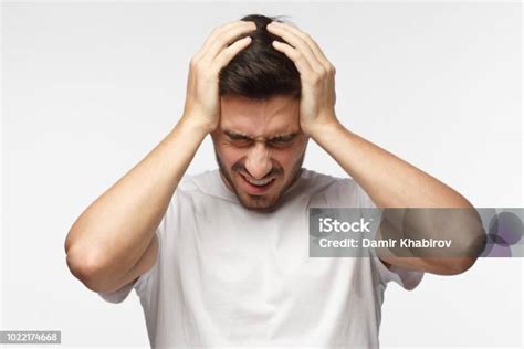 잘생긴 백인의 실내 근접 촬영 심한 두통 또는 외부 심리적 압력에서 고통을 양손으로 그림된에 고립 된 회색 배경 흰색 캐주얼 티셔츠 들고 머리에 남자 두통에 대한 스톡 사진
