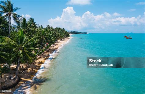 청록색의 맑은 바닷물과 거품이 많은 파도가 있는 하얀 모래 해변 해안의 공중 풍경 어부 보트가 있는 그림 같은 해안선 만의