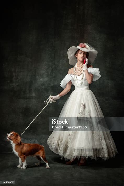 개와 함께 아가씨 어두운 배경에 고립 된 르네상스 스타일의 드레스에서 중세 인물의 이미지에있는 젊은 우아한 여성의 빈티지 초상화 30 34세에 대한 스톡 사진 및 기타