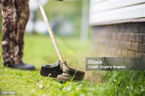 뒤뜰에서 전기 또는 가솔린 잔디 트리머로 키가 큰 풀을 깎는 남자 원예 관리 도구 및 장비 손 깎는 기계로 잔디 트리밍 과정 0