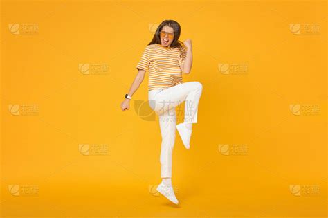 快乐活泼的女孩跳跃在空中，如果她是赢家，孤立在黄色的背景