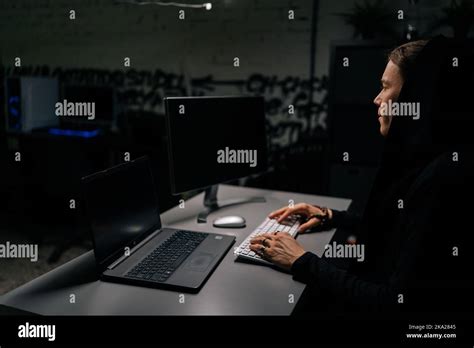 Side View Of Dangerous Hacker Man Wearing Hooded Typing On Wireless
