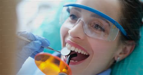 클리닉에서 경화 조명과 치과 기구를 사용하여 여성 환자에게 치아를 치료하는 치과 의사 혁신적인 구강 치료 개념 사진 Unsplash의 건강검진 이미지