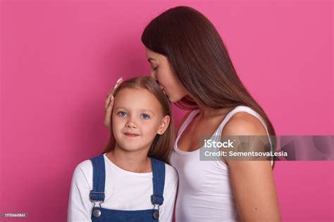 흰색 티셔츠를 입은 여성의 이미지는 귀여운 아이 소녀와 재미를 가지고 있습니다 모텐과 작은 아이는 파스텔 핑크 벽 배경에 고립